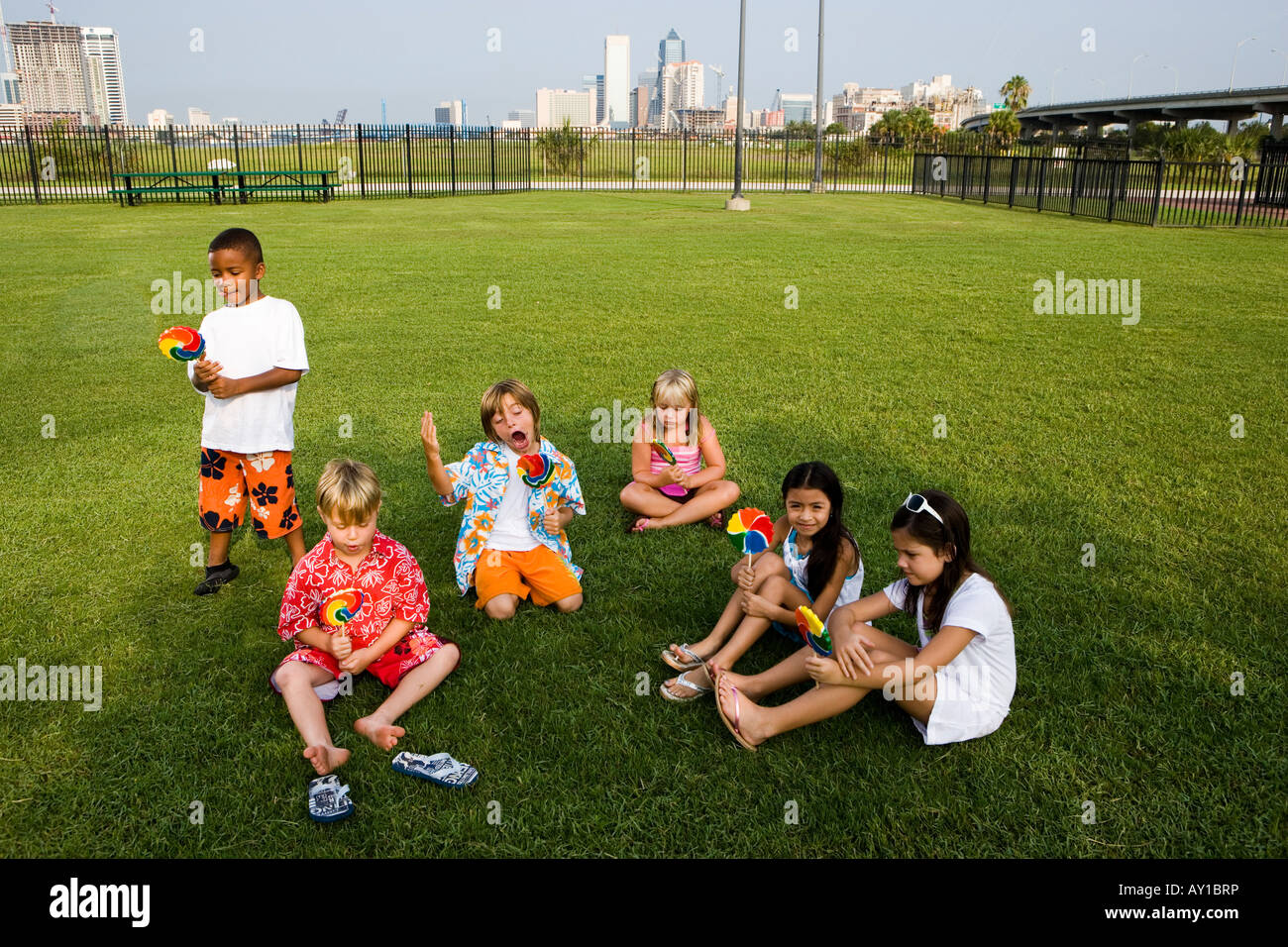 Children sitting on grass and eating lollipops Stock Photo - Alamy