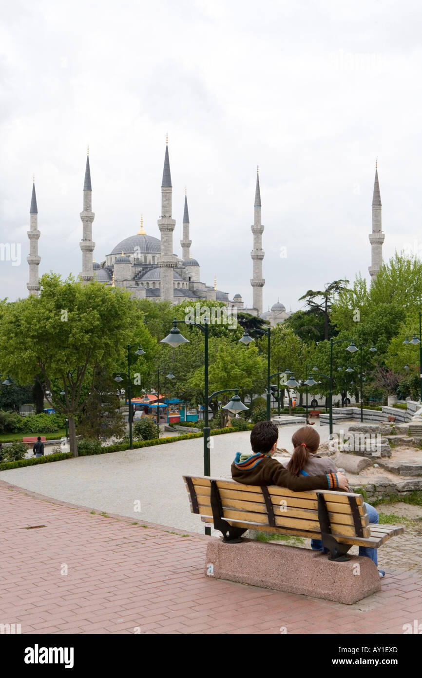 A couple sitting on a bench, admiring the view of the Blue Mosque in ...