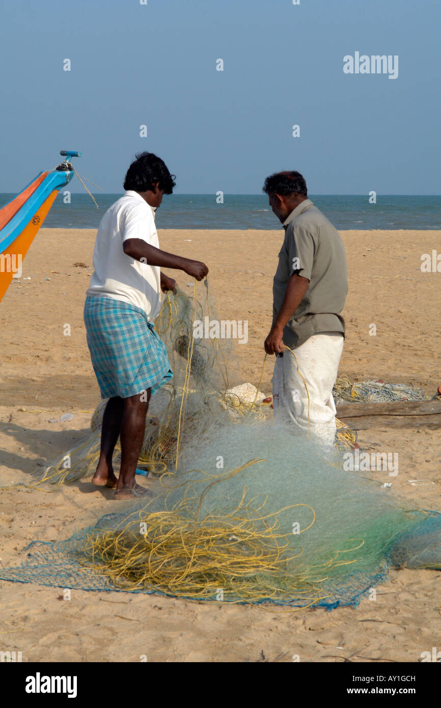 two indian fishermen checking their fishing nets on the beach at ...