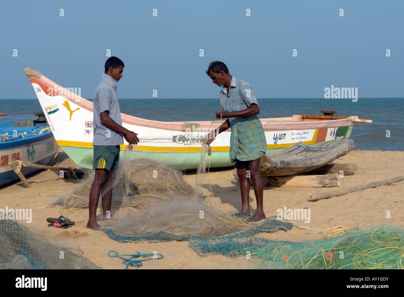 two indian fishermen checking their fishing nets with traditional ...
