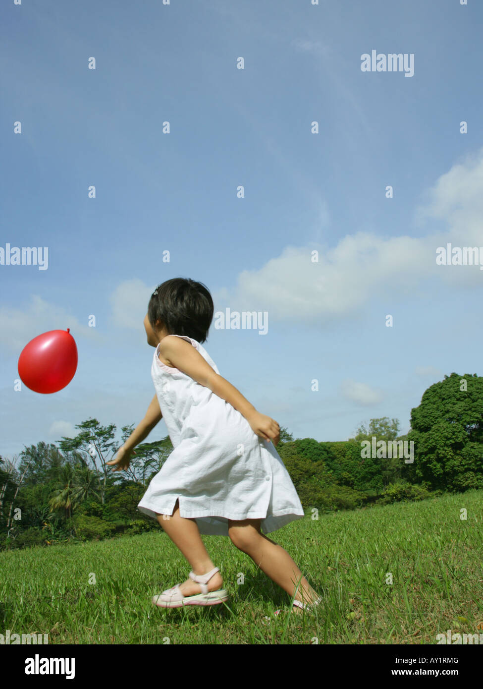 Low angle view of a girl reaching for a balloon Stock Photo - Alamy