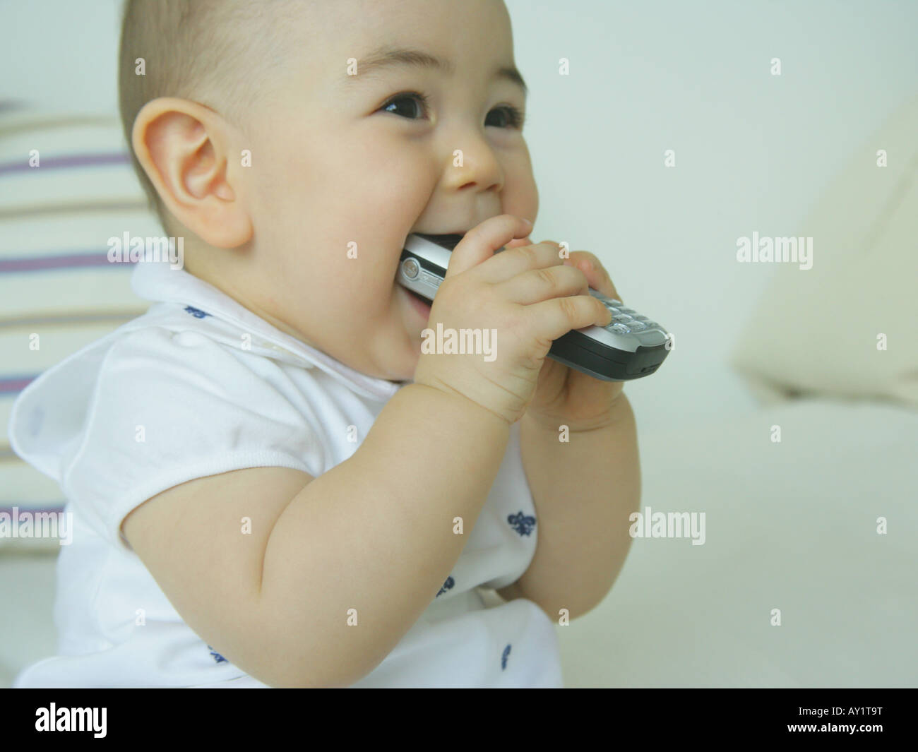 Side profile of a baby girl biting a mobile phone Stock Photo - Alamy