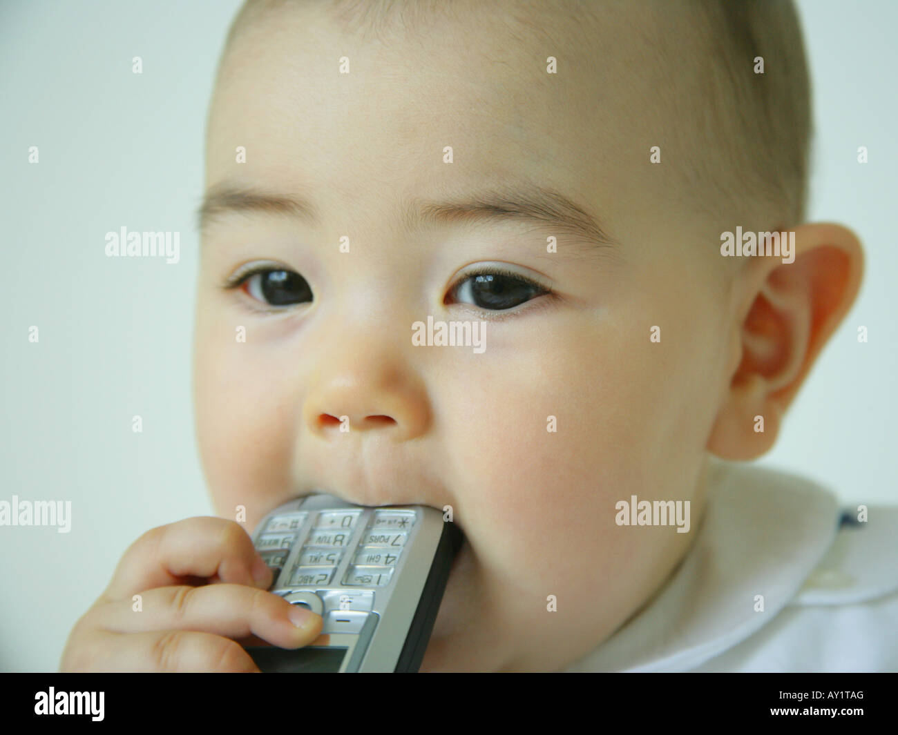 Close-up of a baby girl biting a mobile phone Stock Photo - Alamy