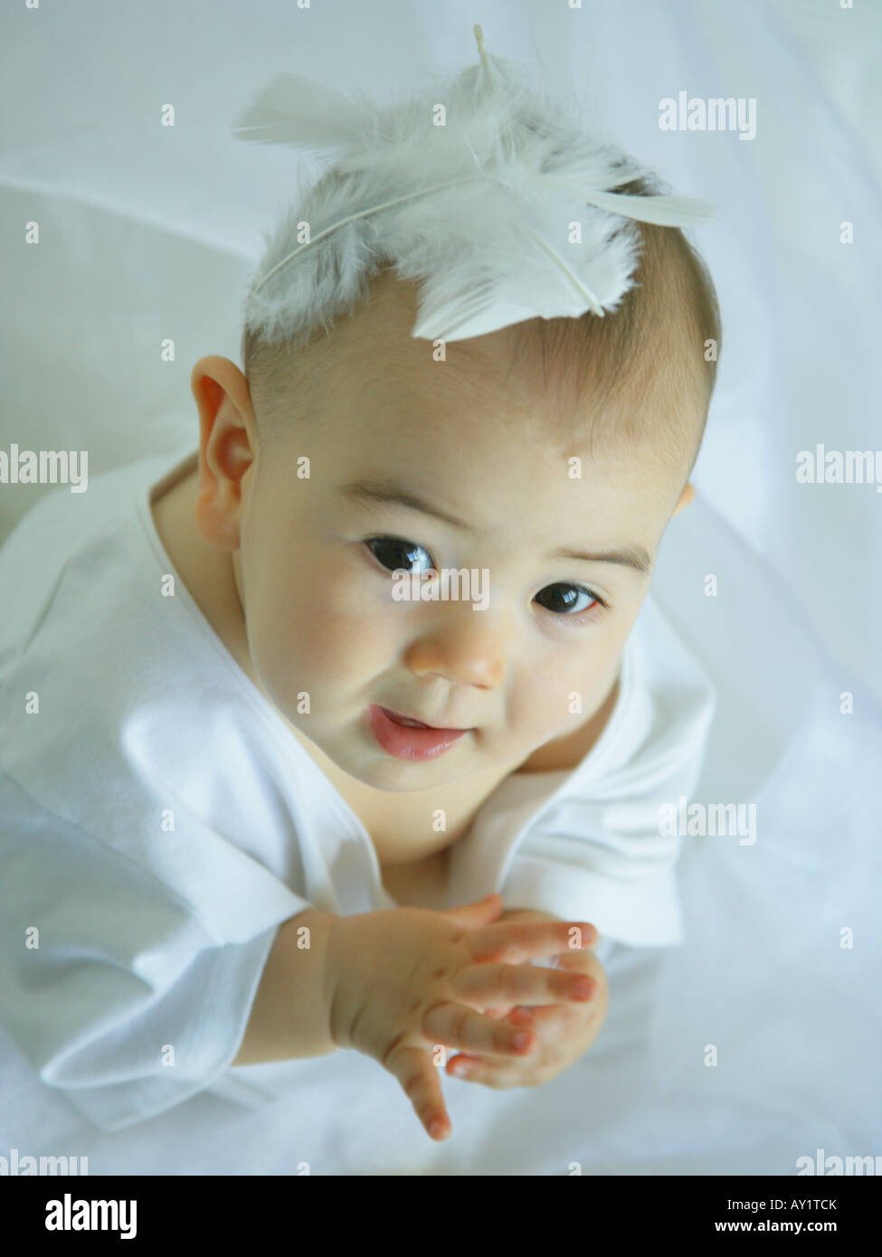Close-up of a baby girl with feathers on her head Stock Photo - Alamy