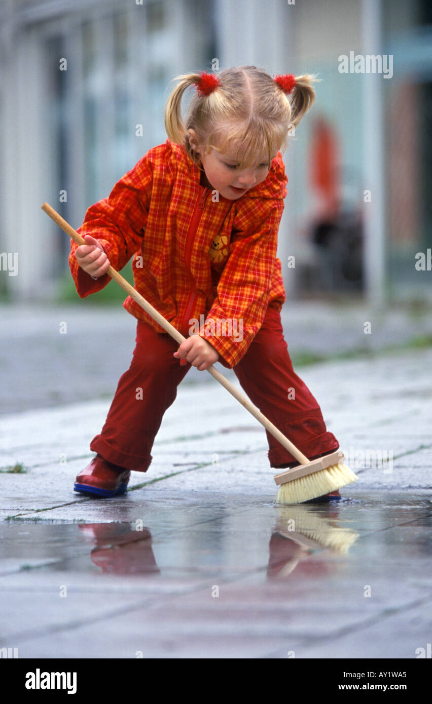 Little girl wiping away water with a little broom Stock Photo - Alamy