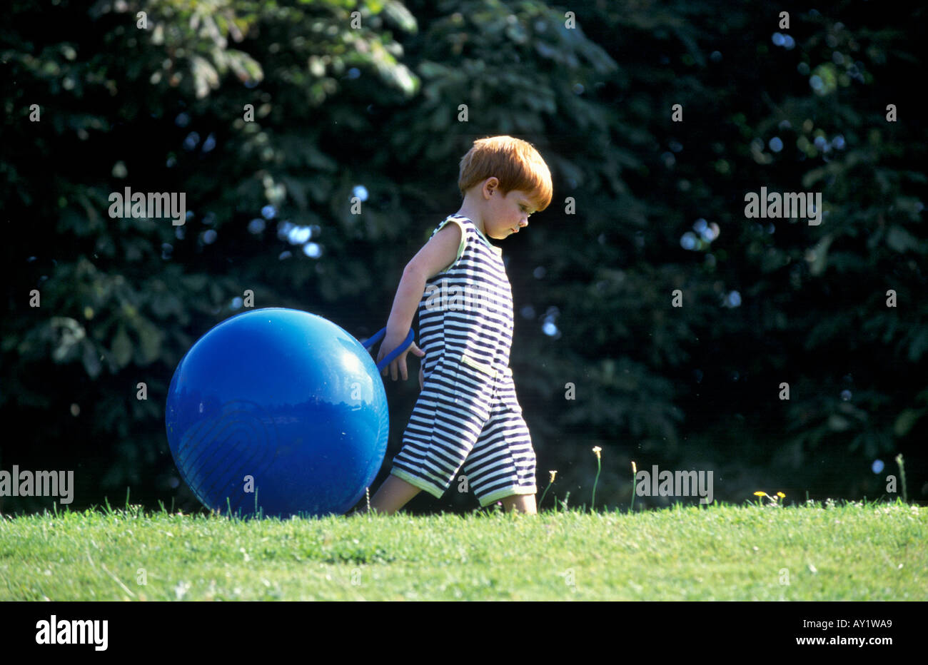 Little boy with a large blue jumping ball Stock Photo - Alamy
