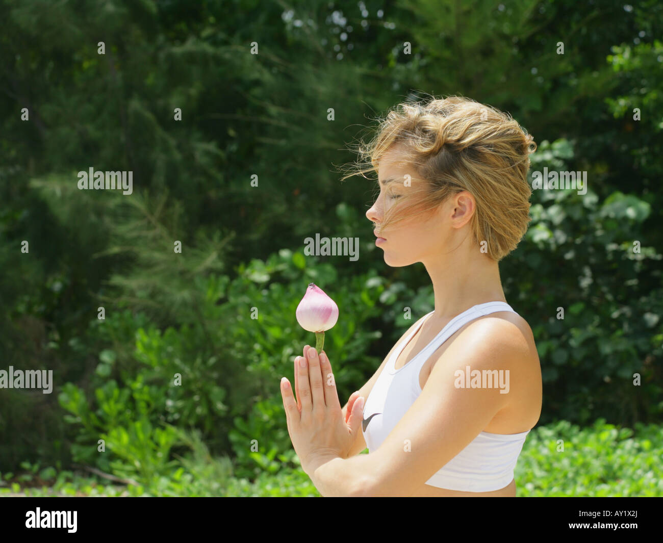 Side profile of a young woman holding a lotus flower in a prayer ...
