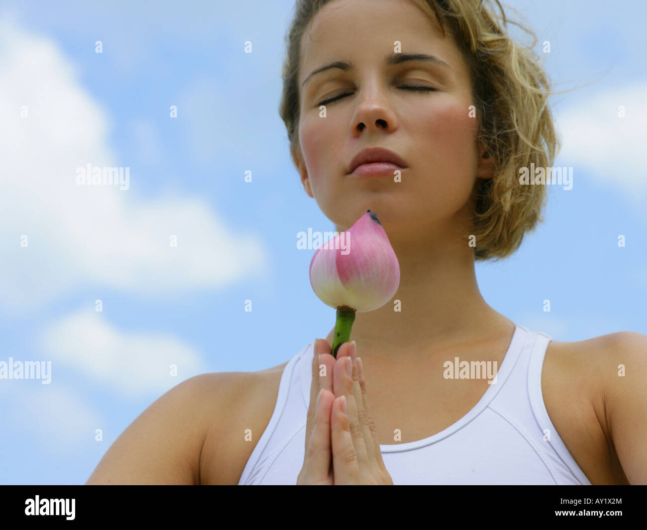 Close-up of a young woman holding a lotus flower in a prayer position ...