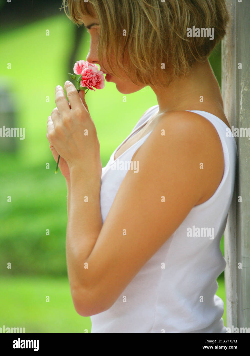 Side profile of a young woman smelling a flower Stock Photo - Alamy