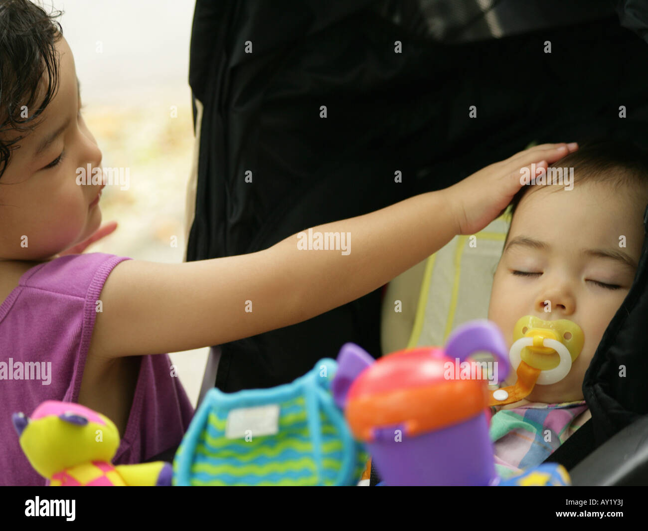 Close-up of a boy touching a baby's head and lying in a stroller Stock ...