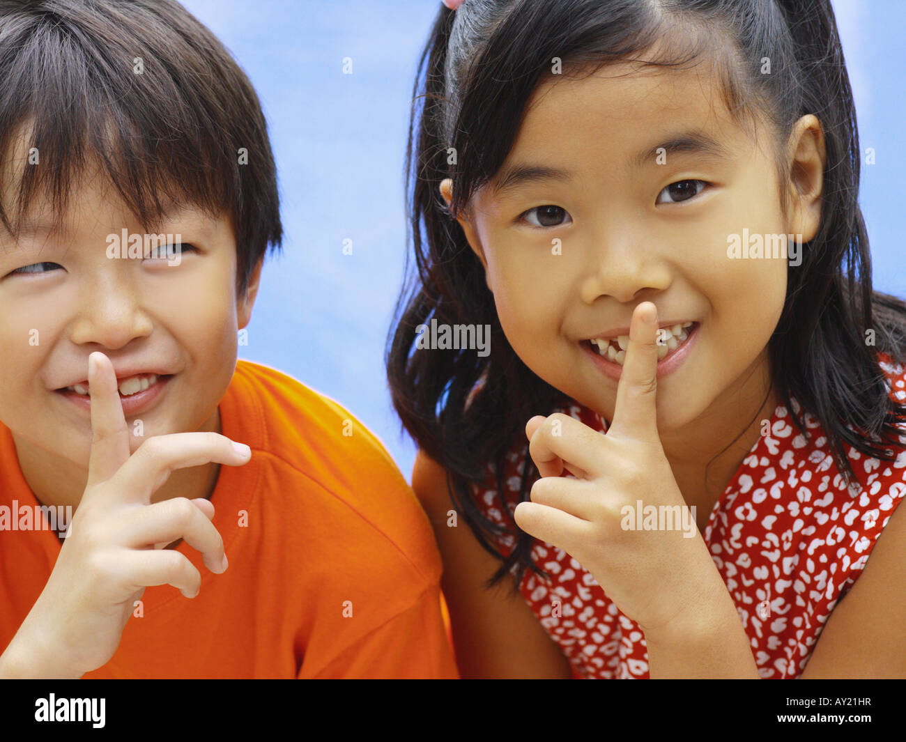 Portrait of a girl and a boy with their fingers on their lips Stock ...