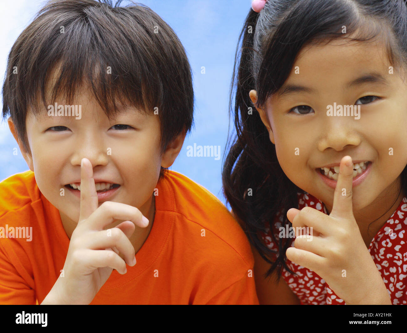 Portrait of a boy and girl with their fingers on their lips Stock Photo ...