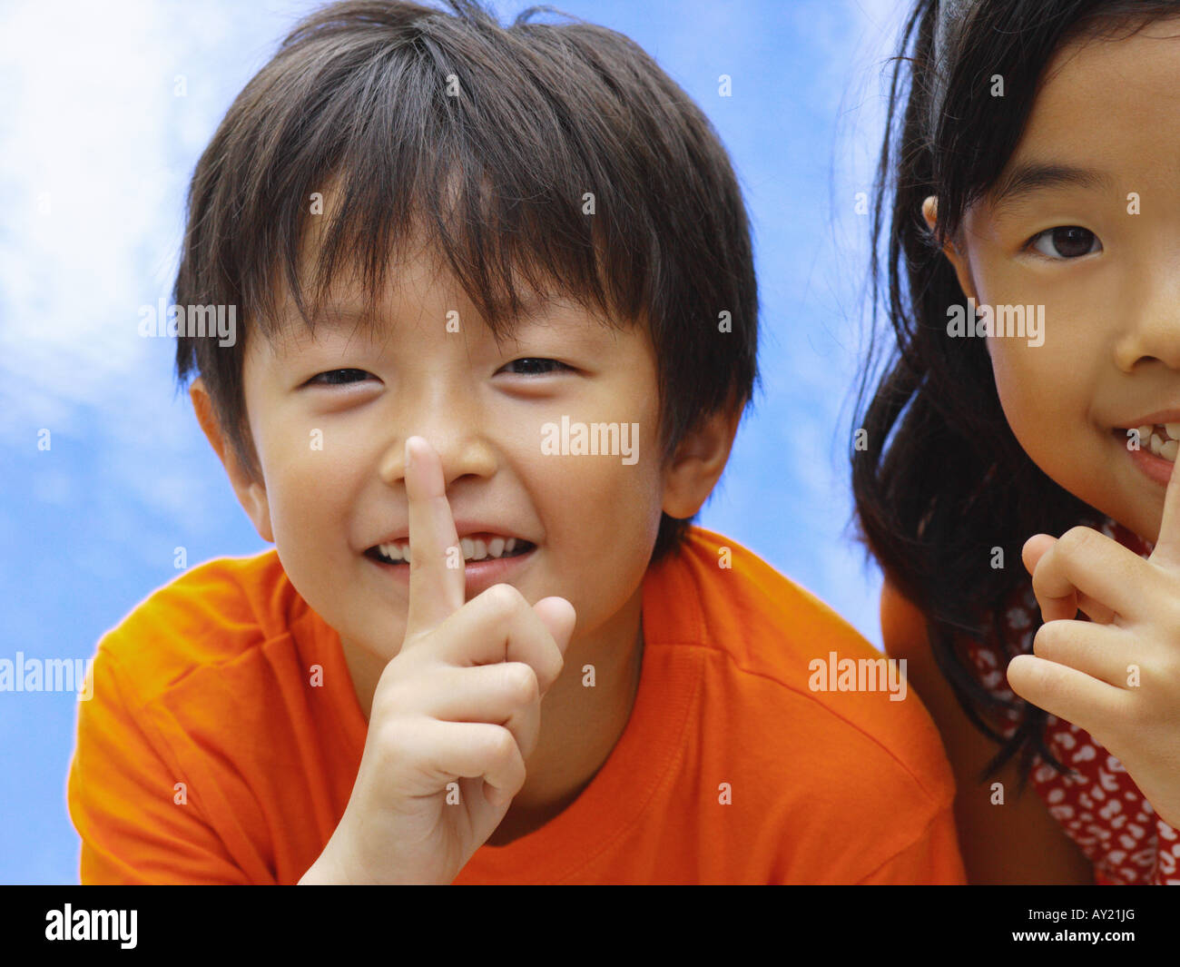 Portrait of a boy and girl with their fingers on their lips Stock Photo ...