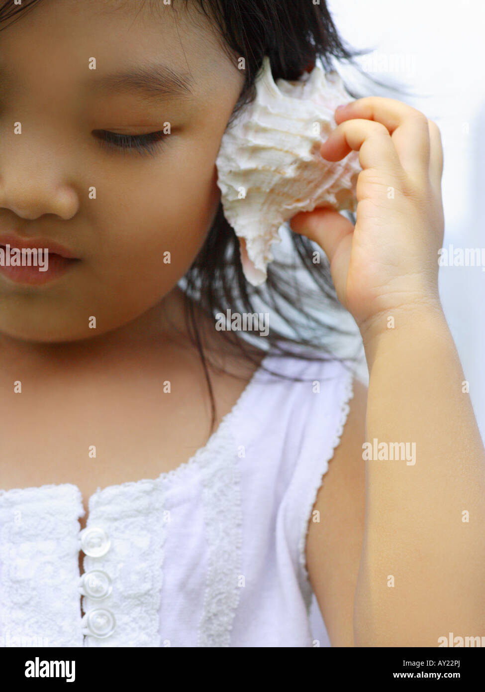 Close-up of a girl listening to a conch shell Stock Photo - Alamy