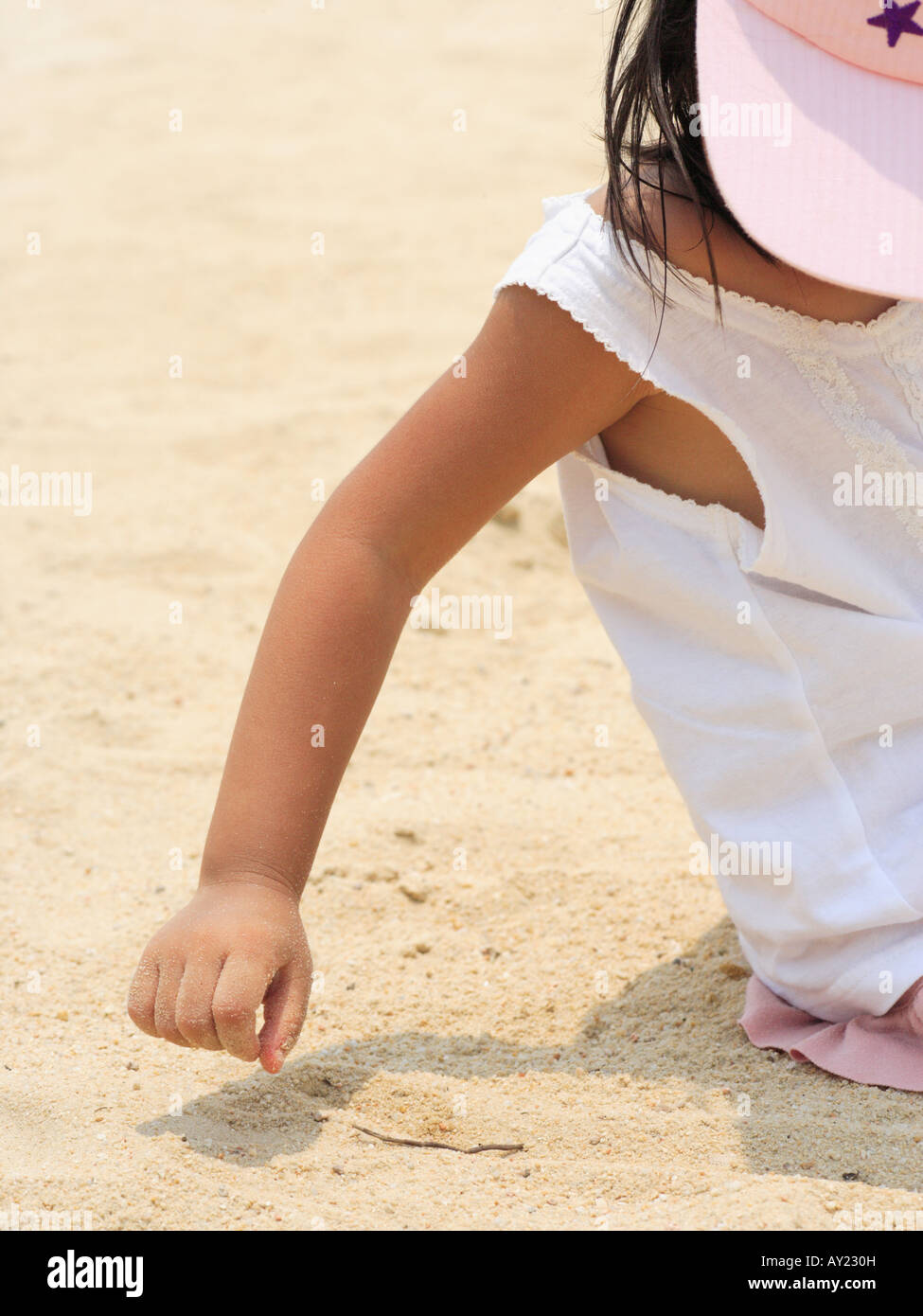 Side profile of a girl playing with sand on the beach Stock Photo - Alamy