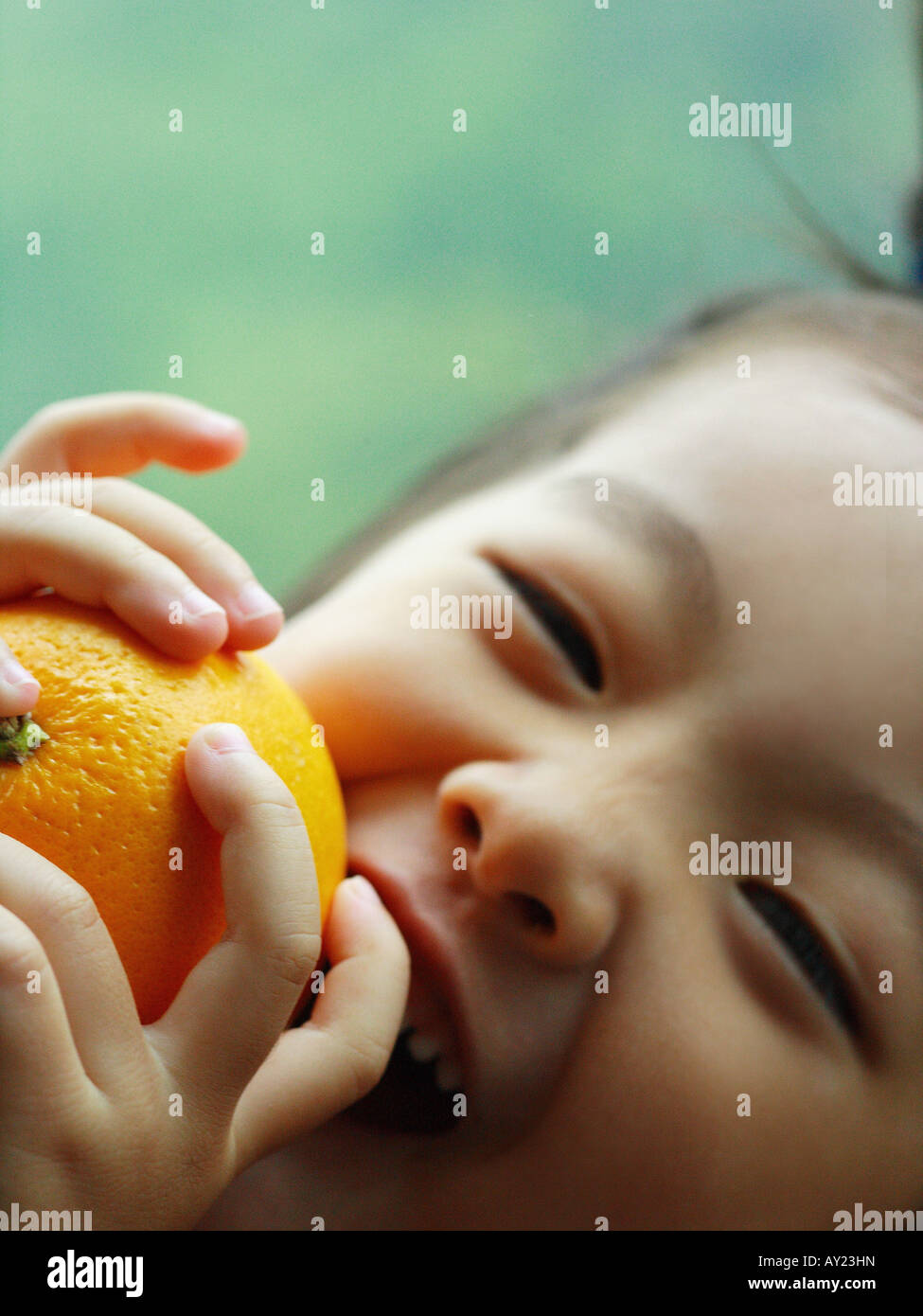 Portrait of a girl biting an orange Stock Photo - Alamy