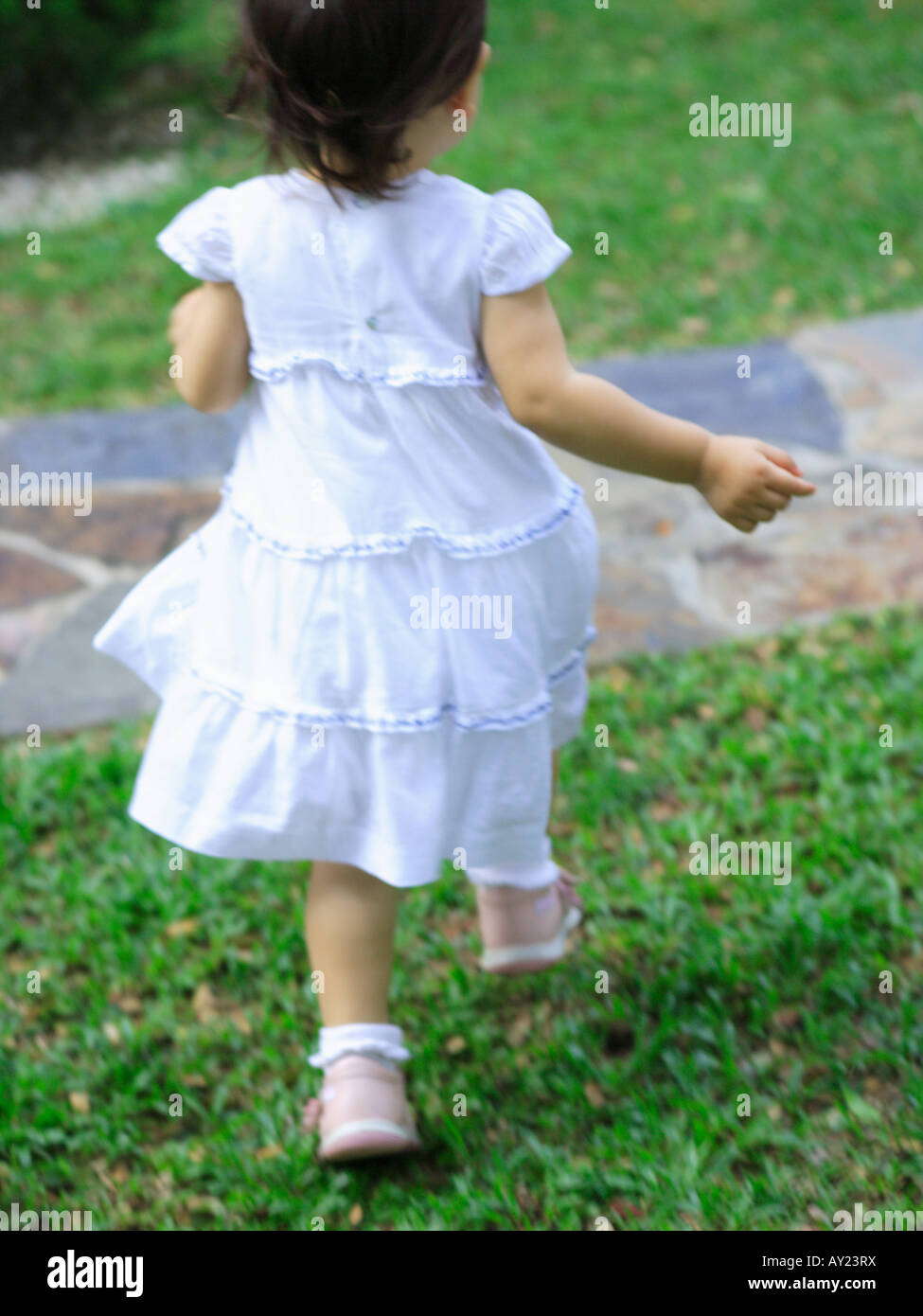 Rear view of a baby girl running in a lawn Stock Photo - Alamy