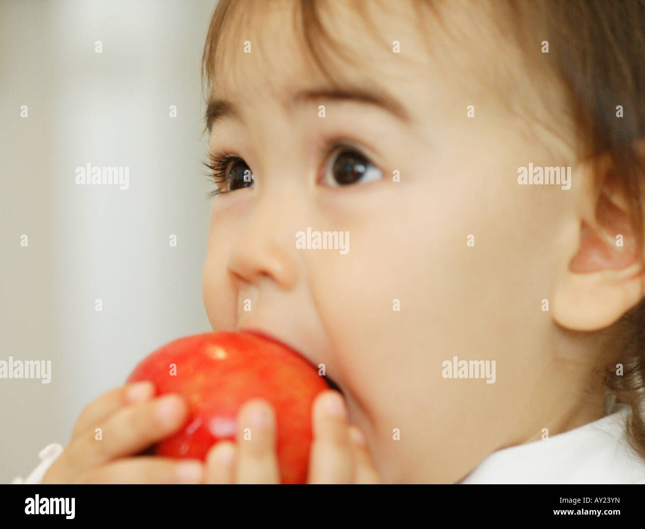 Close-up of a baby girl eating an apple Stock Photo - Alamy