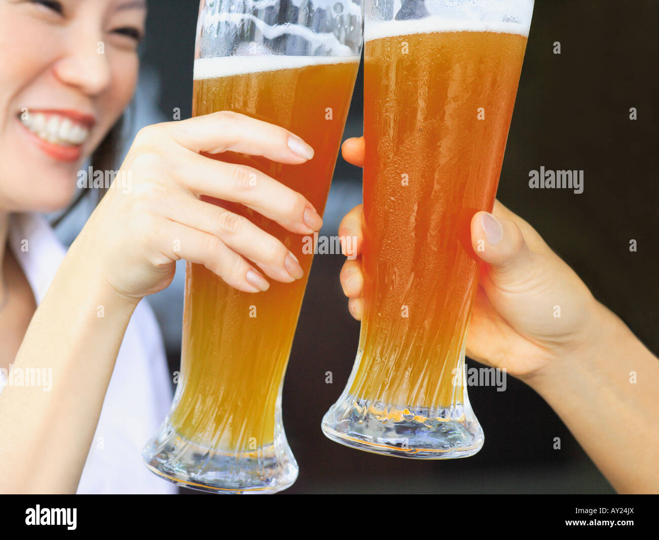 Close-up of a woman with her friend toasting beer glasses Stock Photo ...