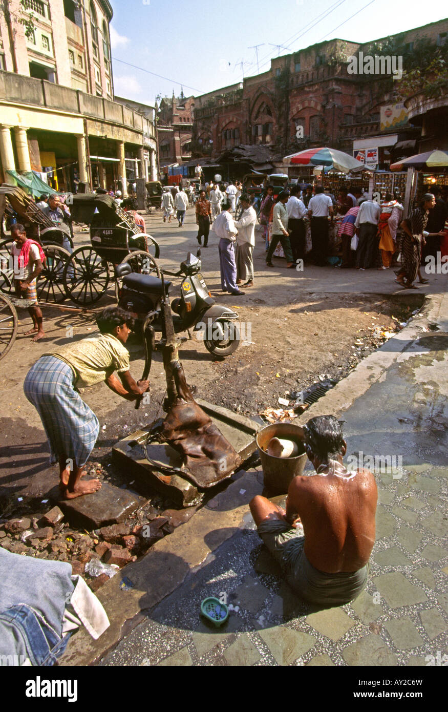 India West Bengal Calcutta man filling goatskin with water as another ...