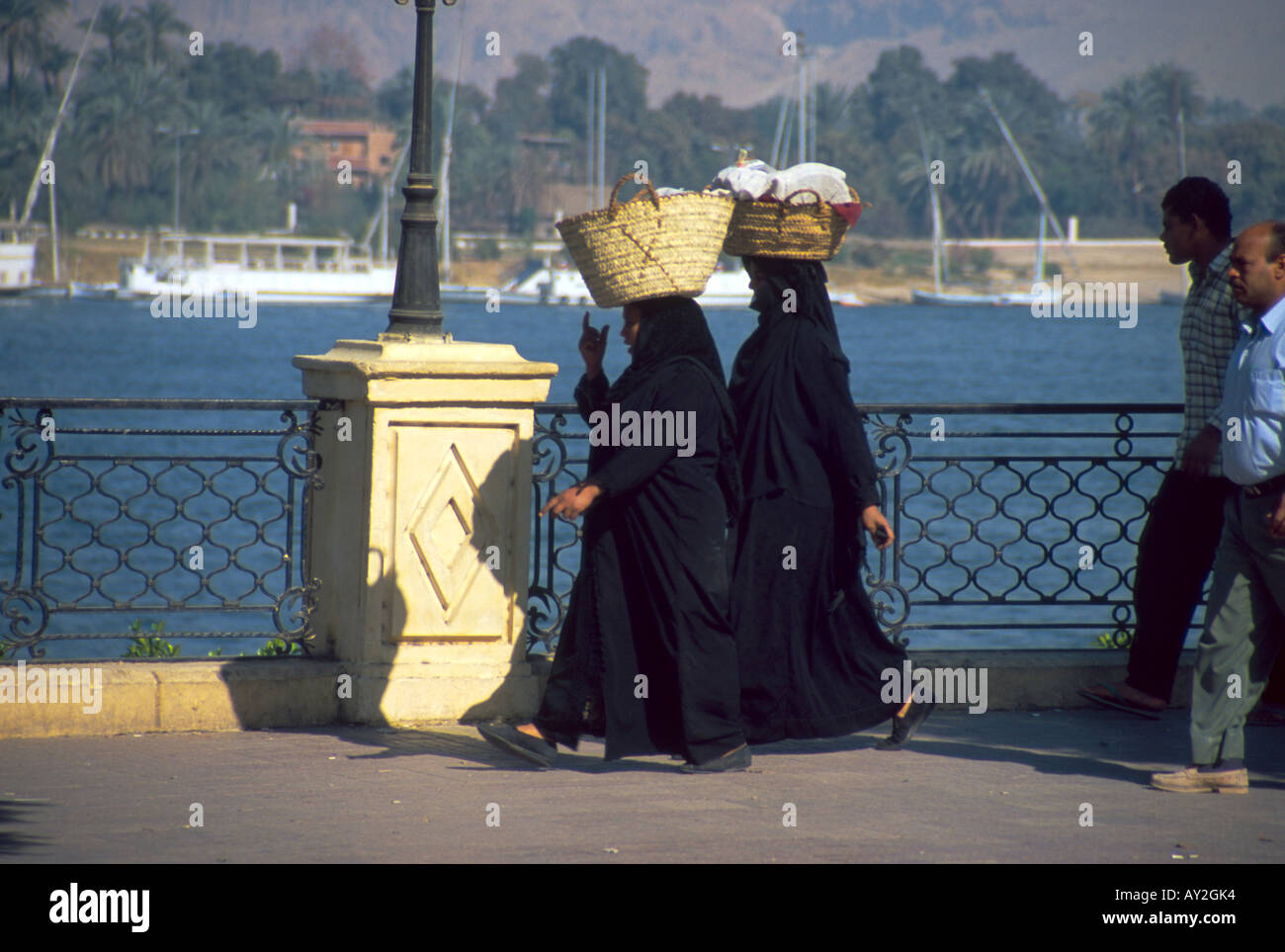 Muslim women carrying baskets on there heads by the Nile river in Luxor ...