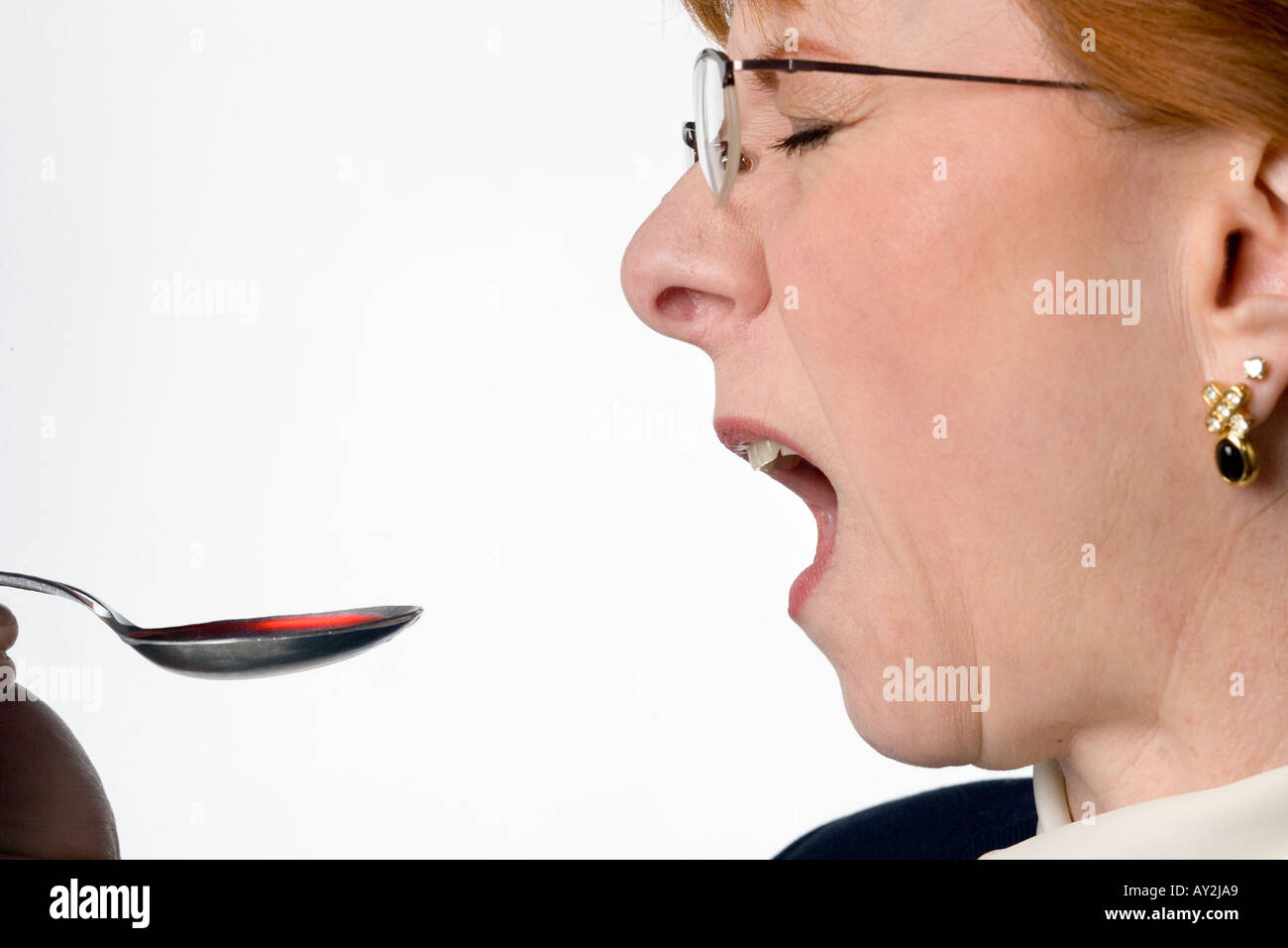 Woman with a spoonful of bad tasting medicine Stock Photo - Alamy
