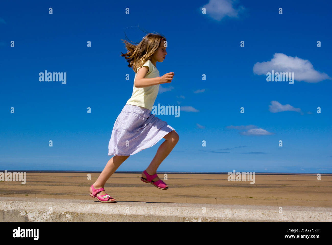 girl child running along seaside wall Stock Photo - Alamy