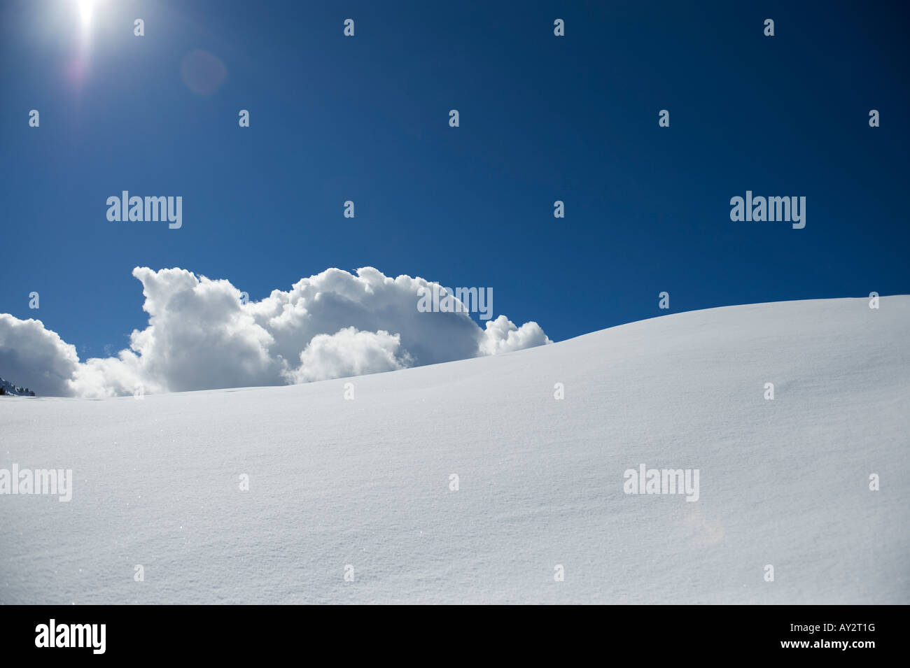 White Cumulus clouds developing over a snow covered hillside with blue ...