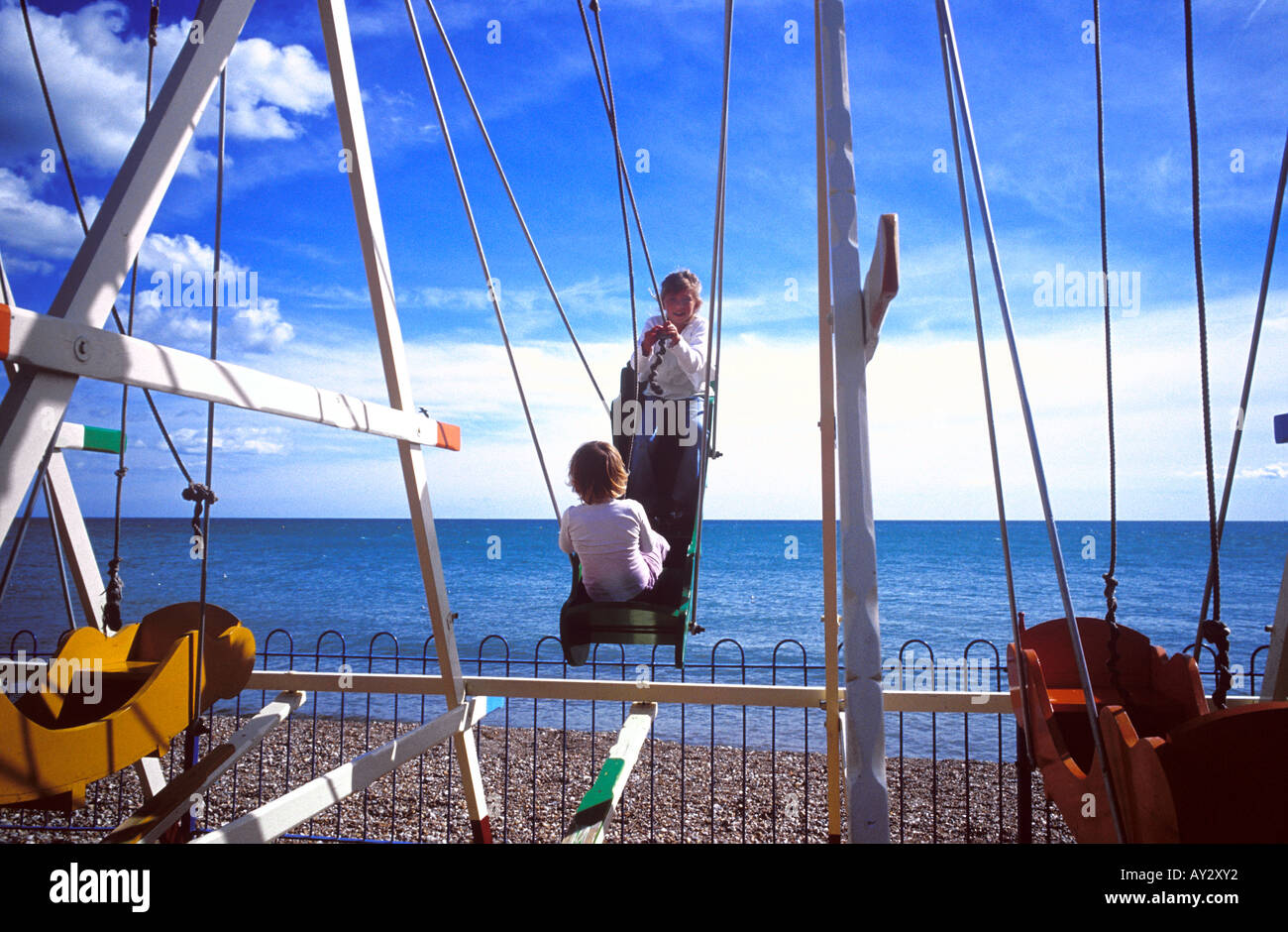 Young children playing on a funfair swing at the seaside in the UK ...