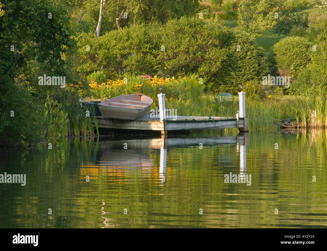 A pink rowboat sitting on a small wooden dock on a summer's afternoon ...