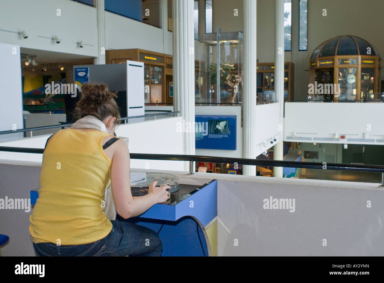 Female college student looking through a microscope in an exhibit in a ...