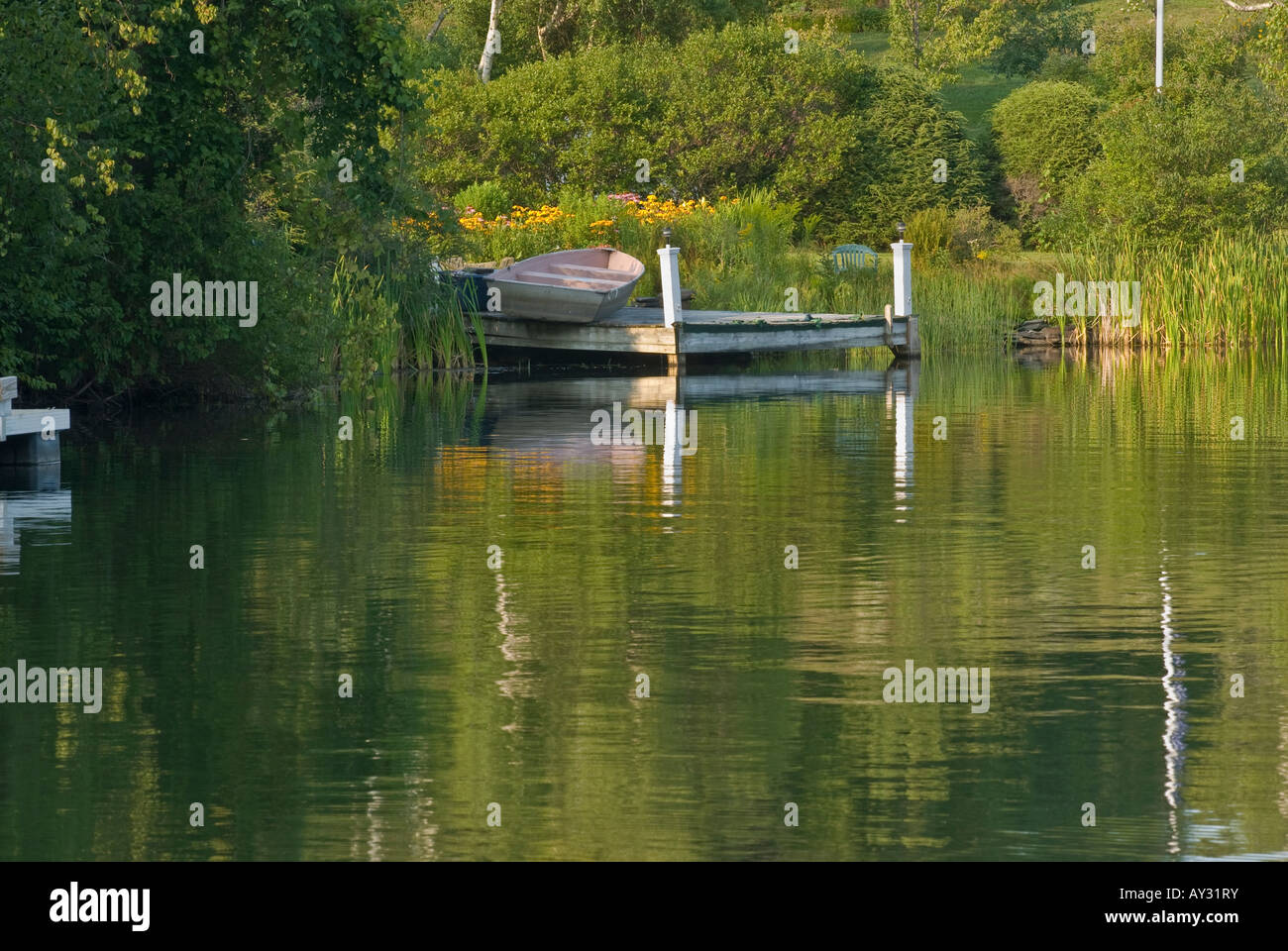 A pink rowboat sitting on a small wooden dock on a summer's afternoon ...