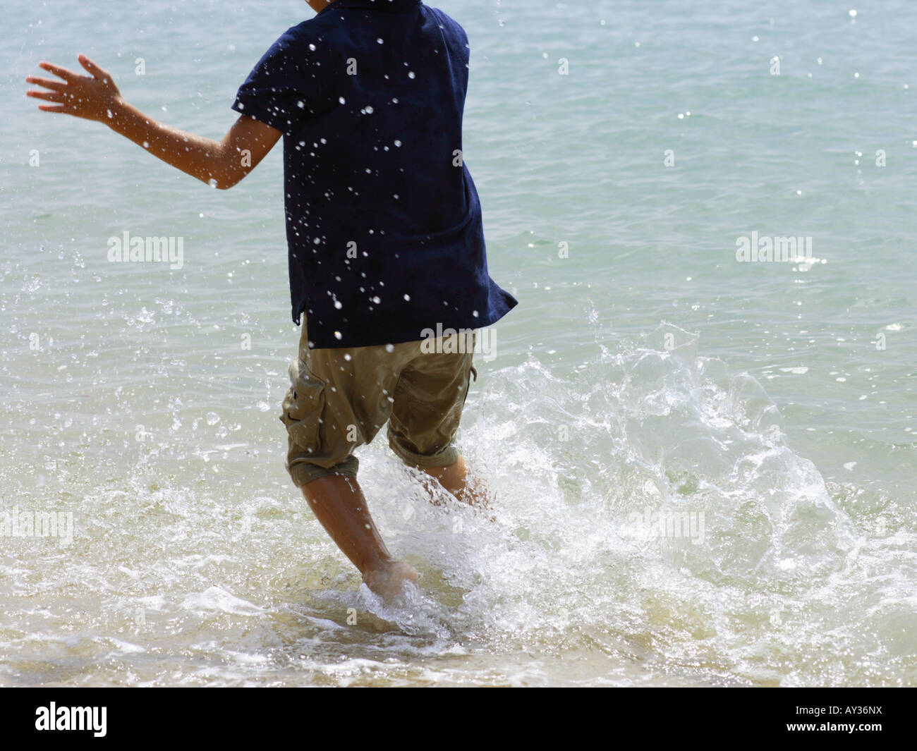 Rear view of a boy playing in water Stock Photo - Alamy