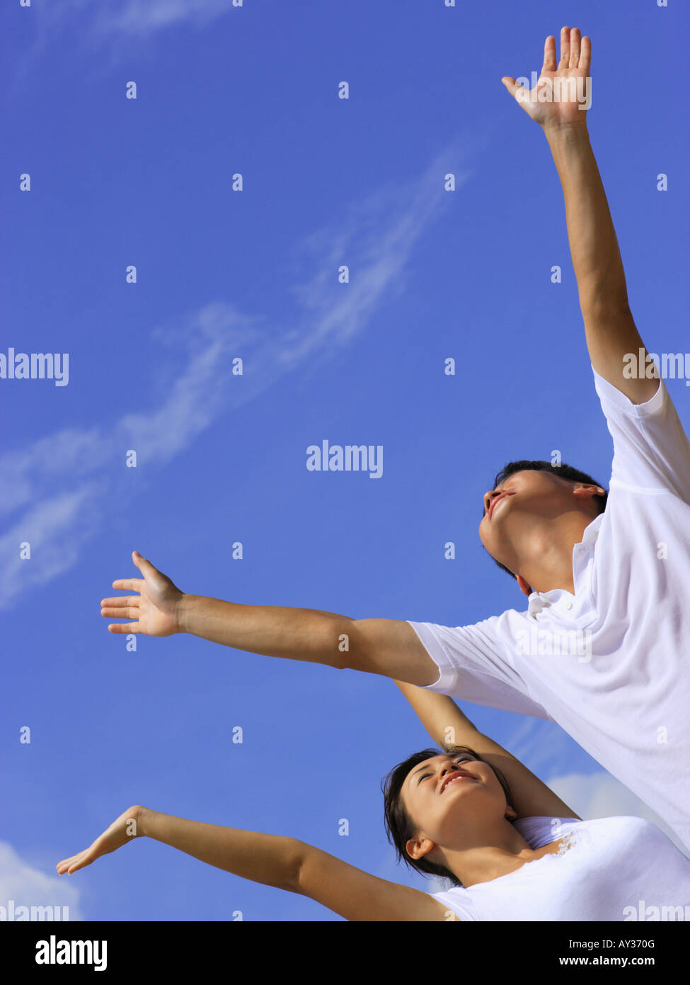 Low angle view of a mid adult couple smiling with their arms raised ...