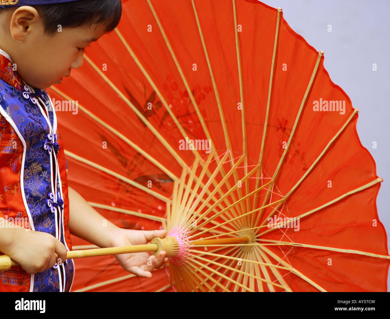Side view of a boy wearing traditional clothing and holding a parasol ...