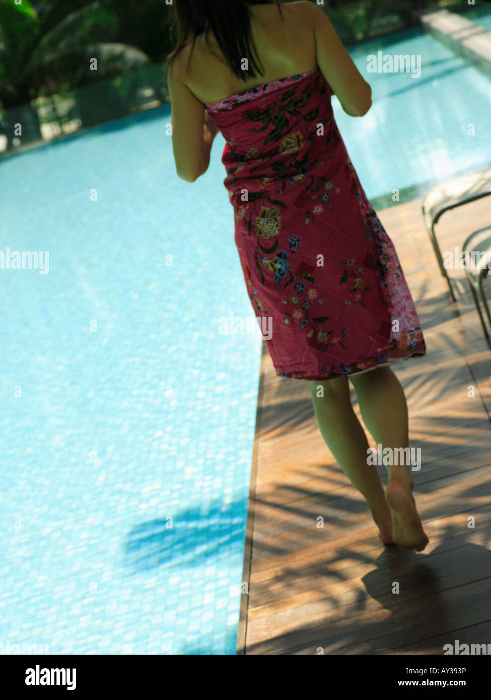 Rear view of a woman walking at the poolside Stock Photo - Alamy