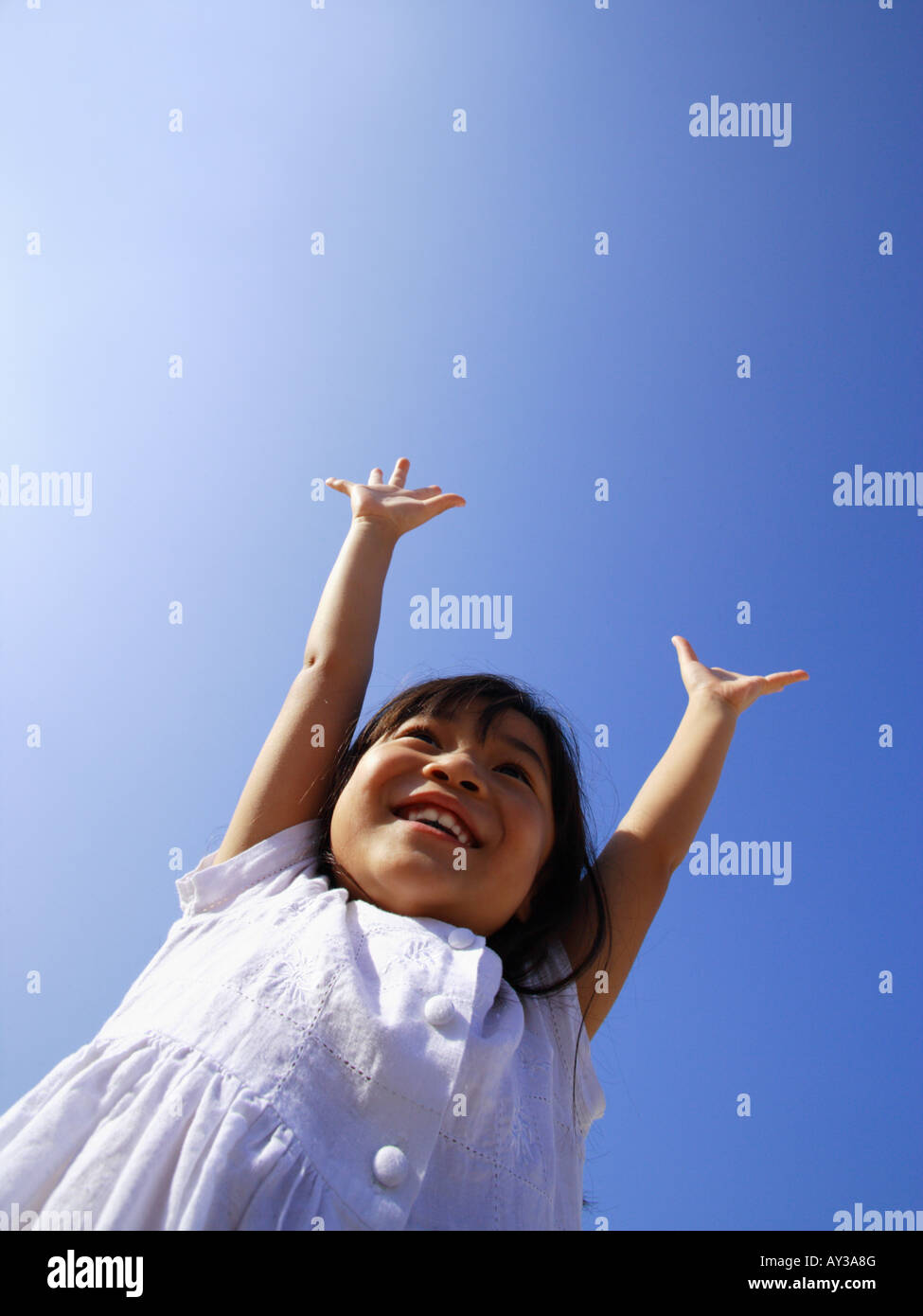 Low angle view of a girl standing with her arms raised Stock Photo - Alamy