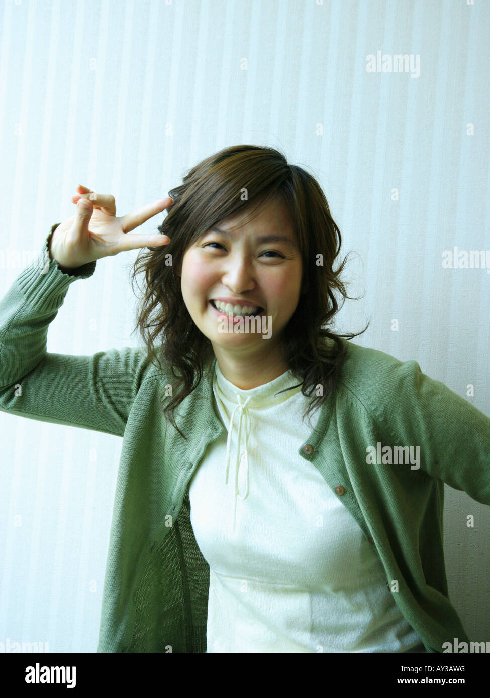 Portrait of a young woman showing a peace sign and smiling Stock Photo ...