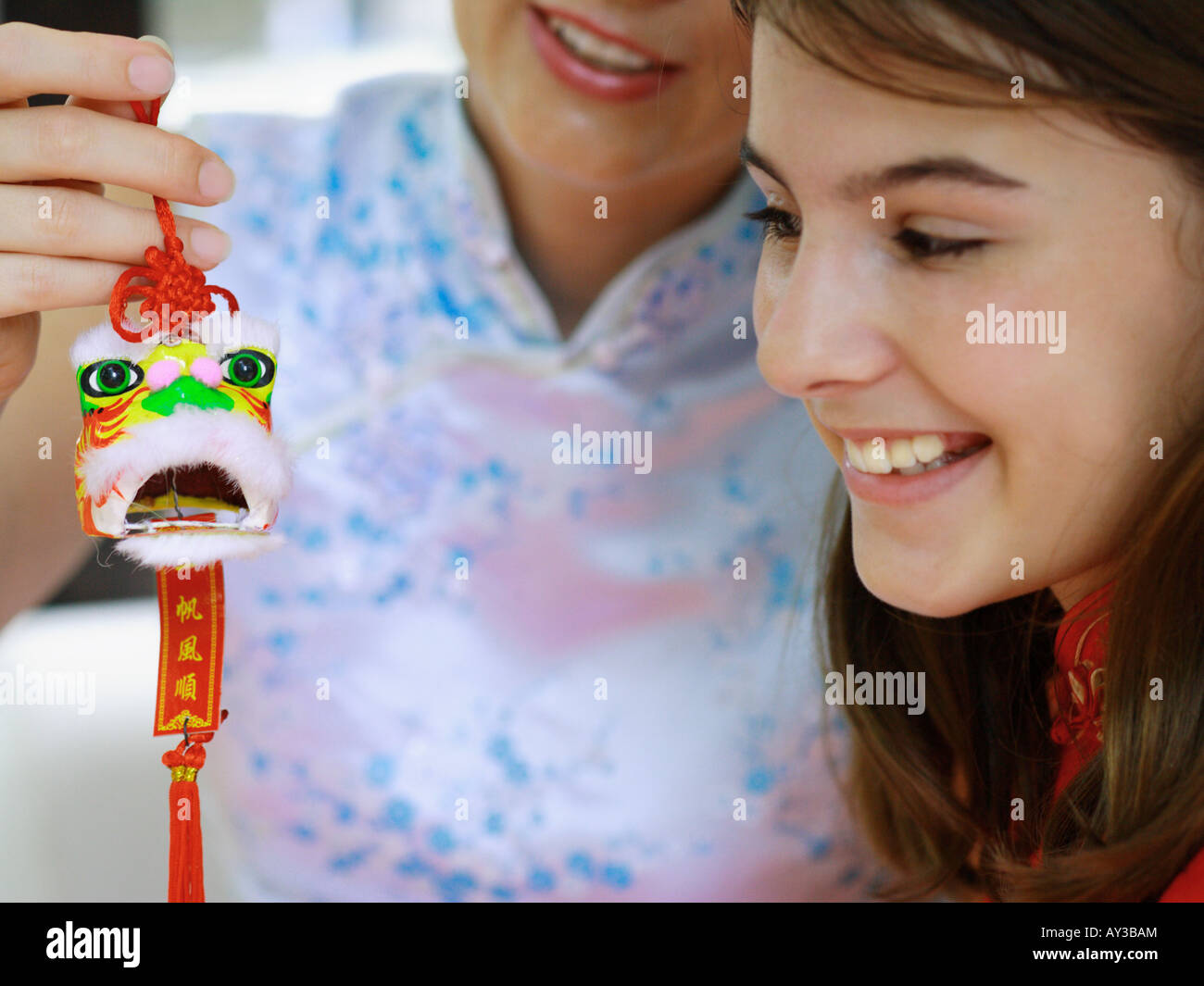 Close-up of a teenage girl with her mother holding a good luck charm ...