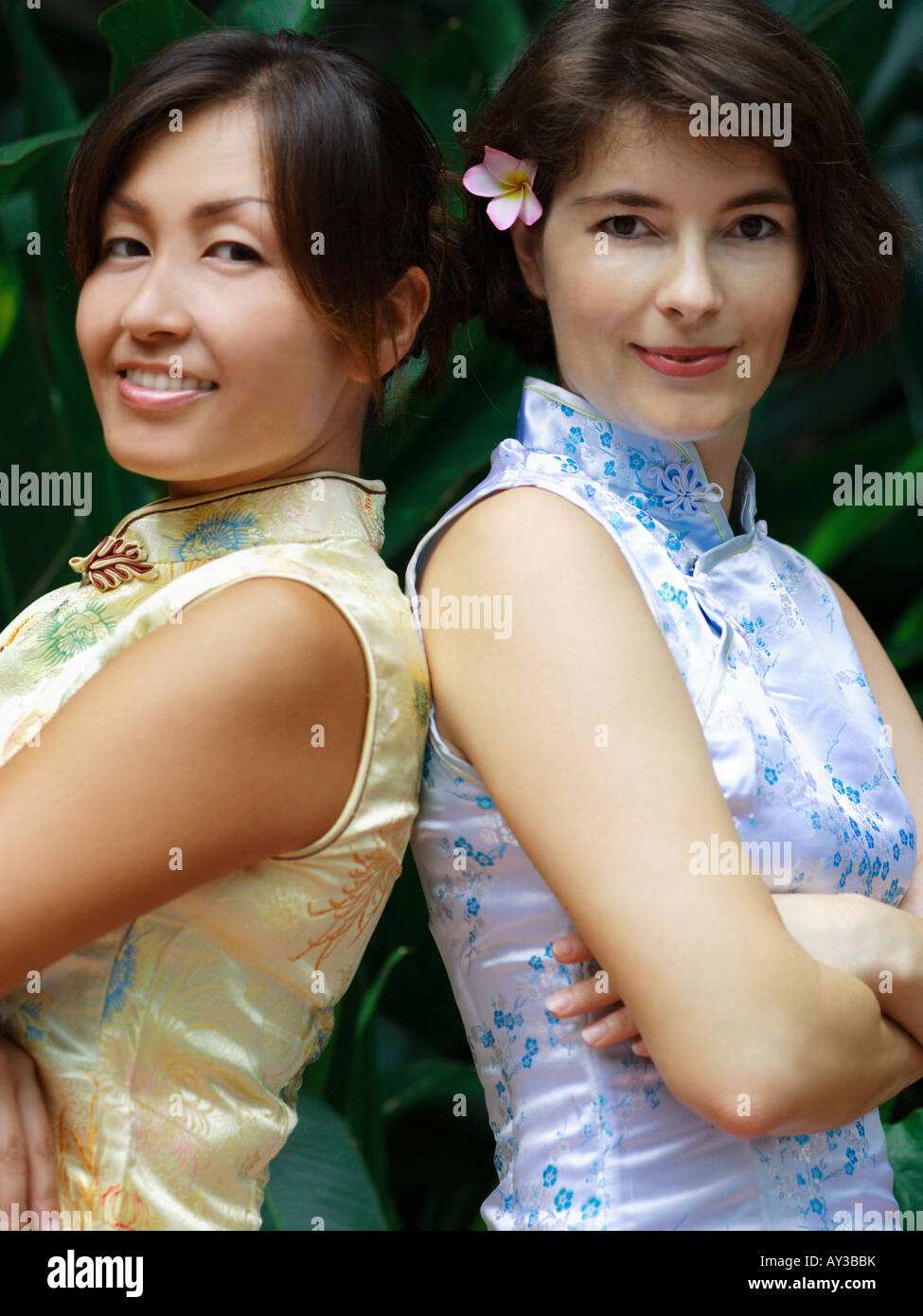 Portrait of two women standing back to back and smiling Stock Photo - Alamy