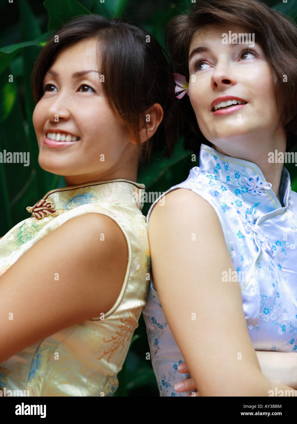 Portrait of two women standing back to back and smiling Stock Photo - Alamy