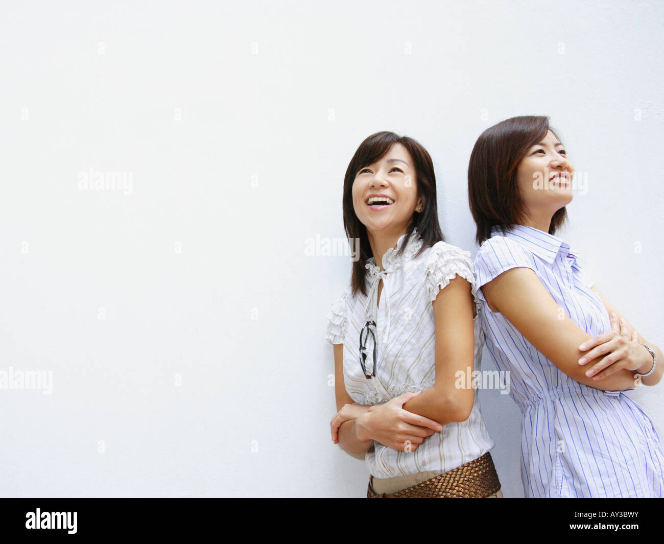 Side profile of two businesswoman standing back to back and smiling ...