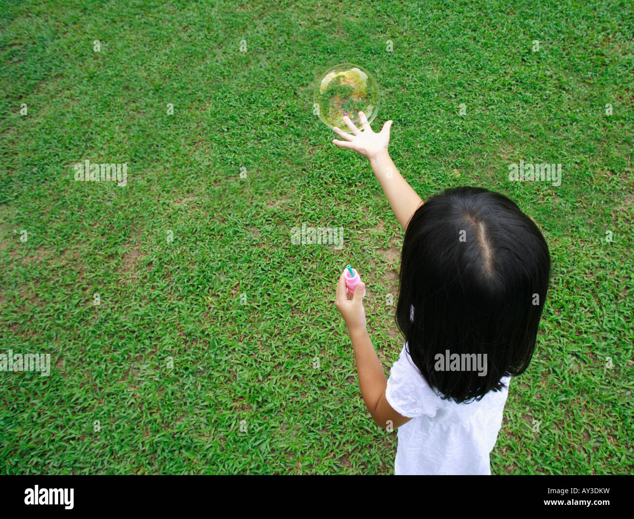 High angle view of a girl trying to hold a bubble Stock Photo - Alamy