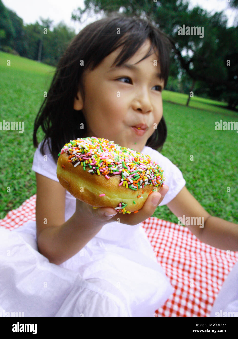 Close-up of a girl holding a donut and sitting in a park Stock Photo ...