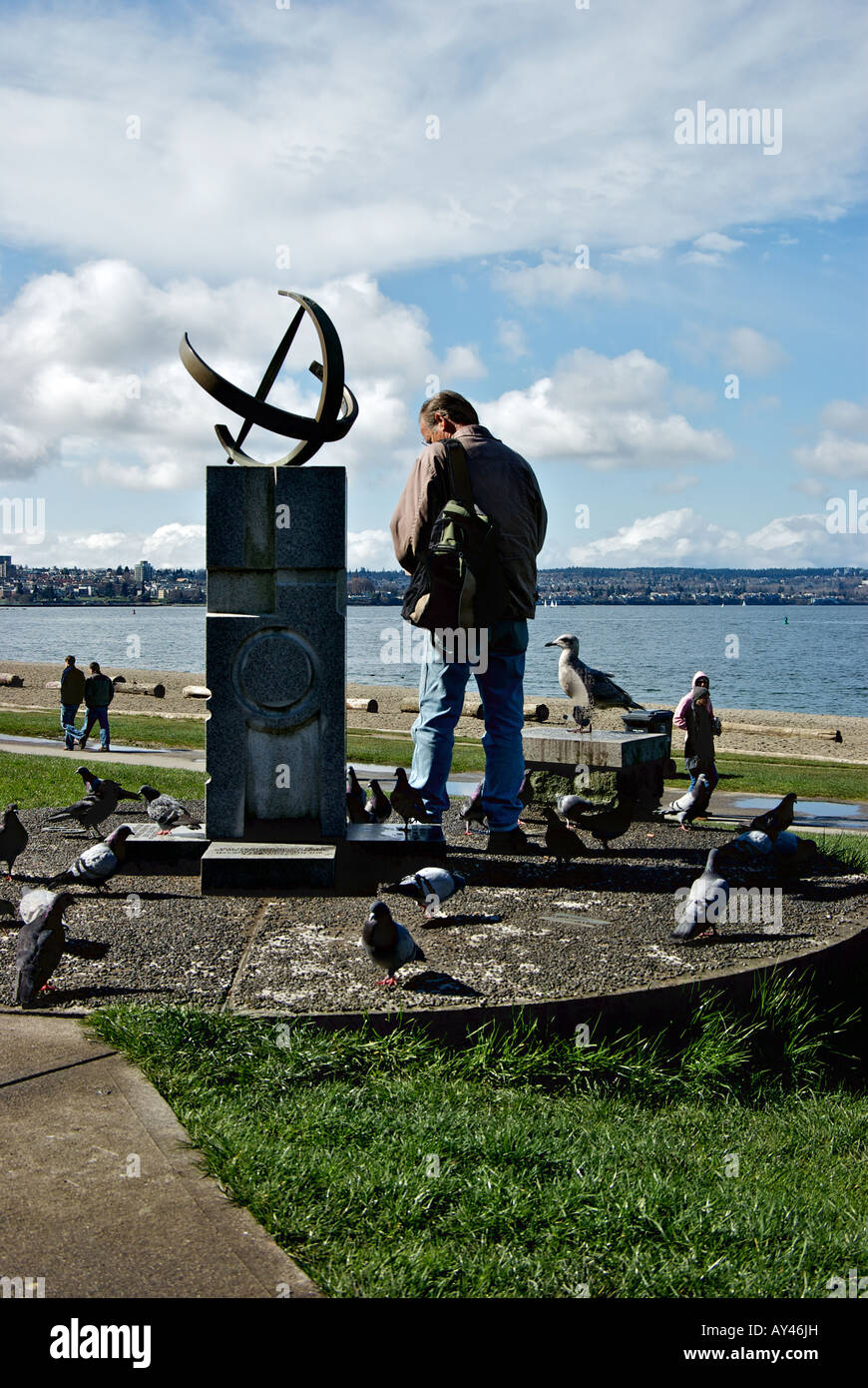 Man feeding birds at sundial sculpture at English Bay beach in the West ...