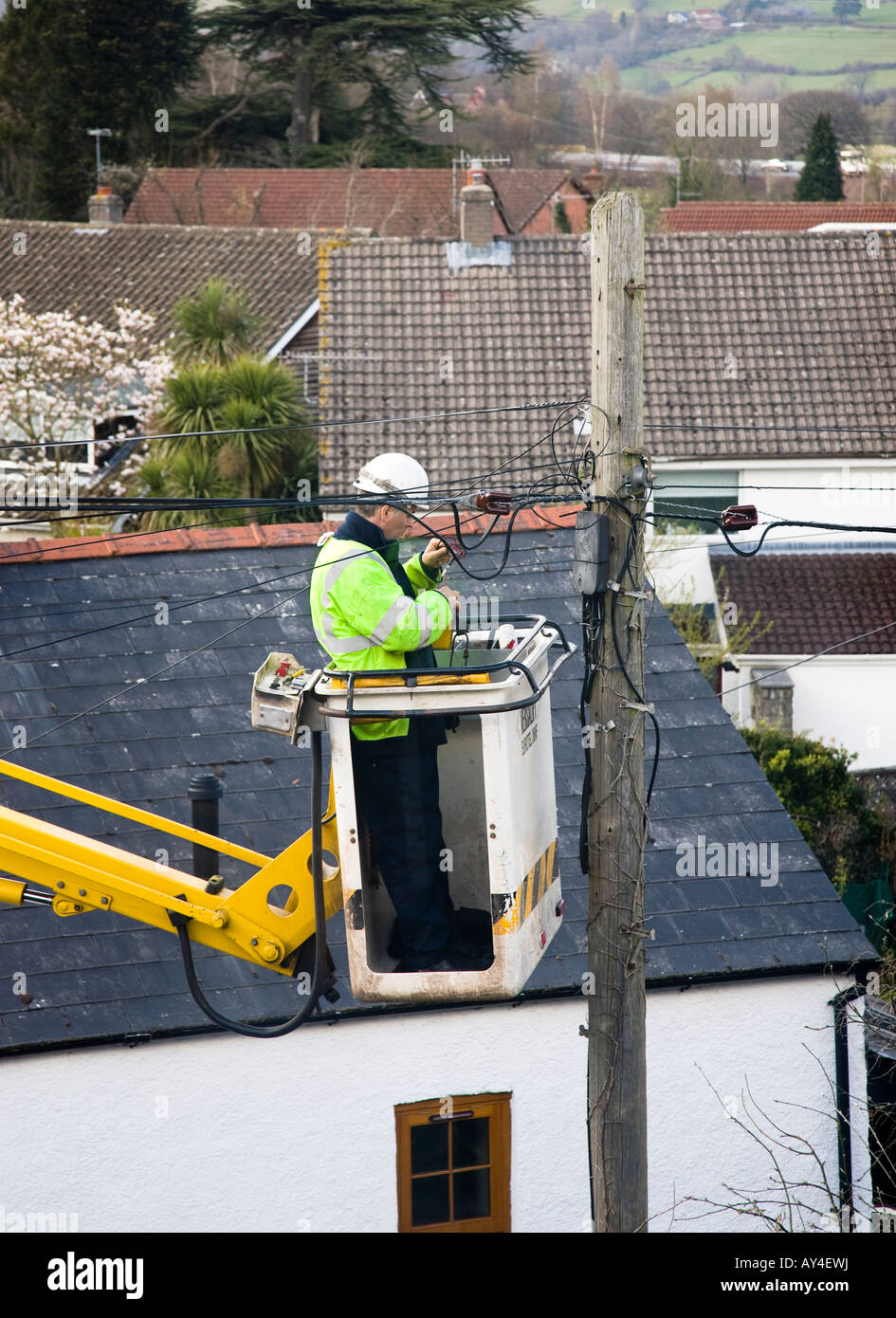 Engineer working at height using mechanical lift repairing telephone ...