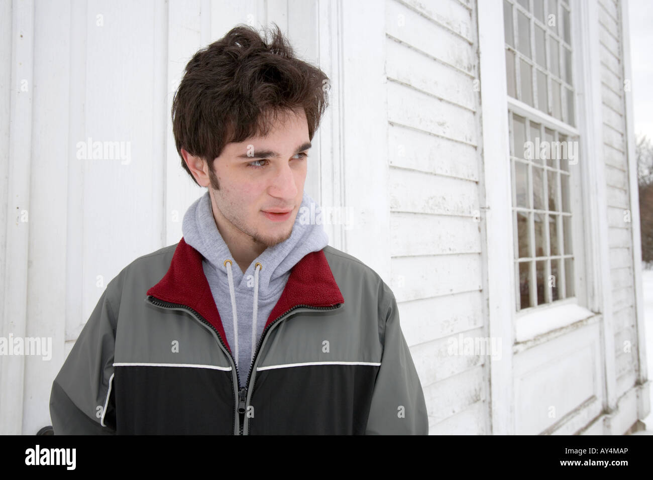 Young Man stands outside by old building It is winter time and he wears ...