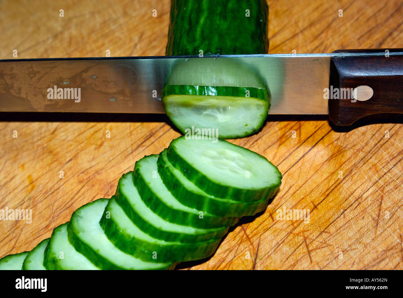 Sliced English Cucumber with sharp kitchen knife on wooden cutting ...