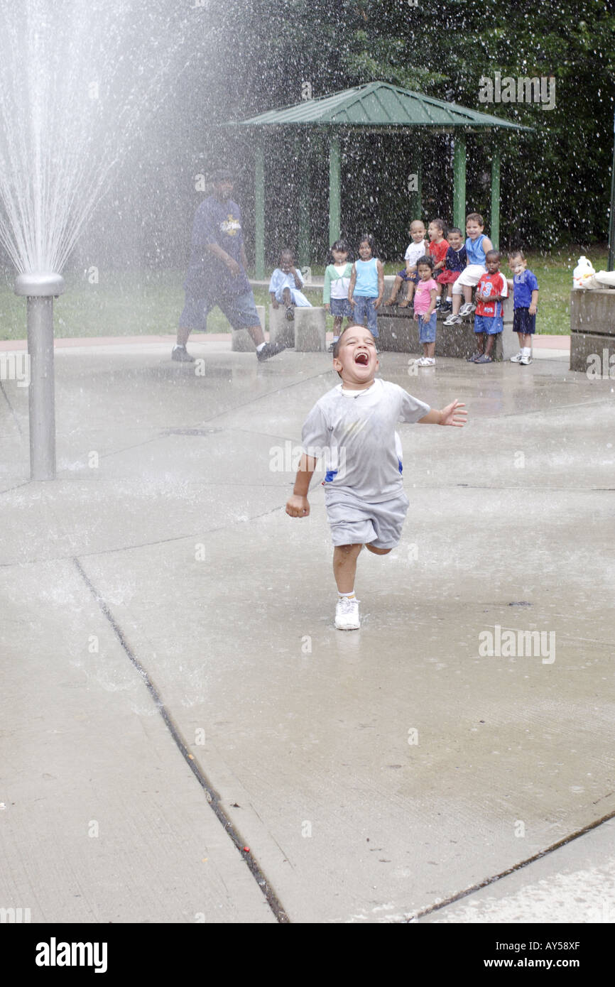 4 year old boy running through a water sprinkler at a playground Stock ...