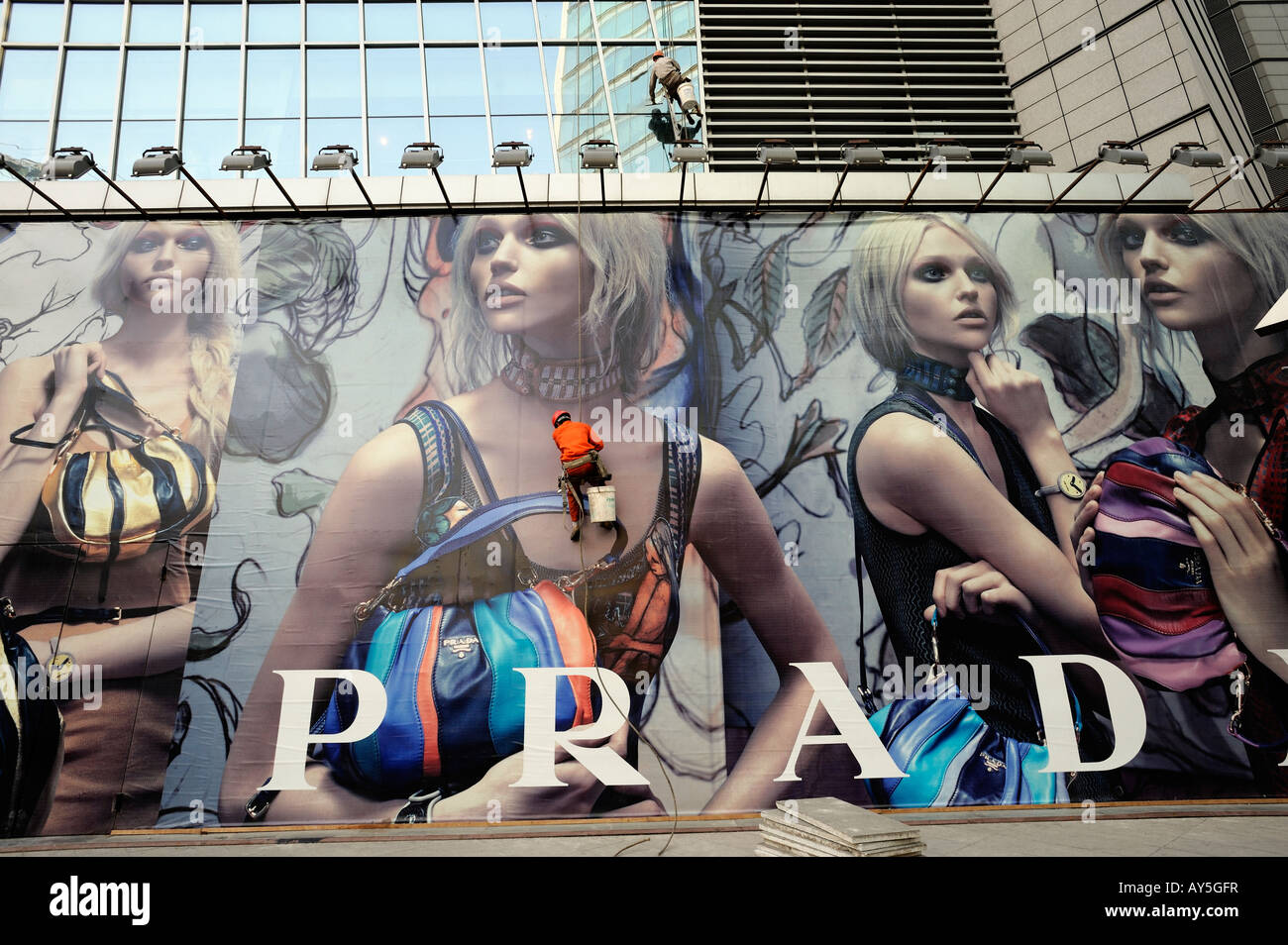 Workers cleaning windows above a huge PRADA billboard at Shin Kong ...